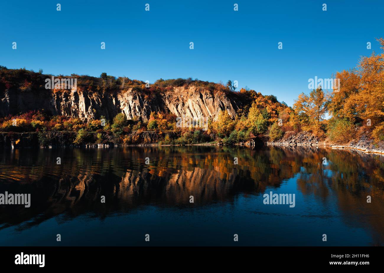 Golden autumn with colourful trees in old flooded quarry. Rocks, lake ...