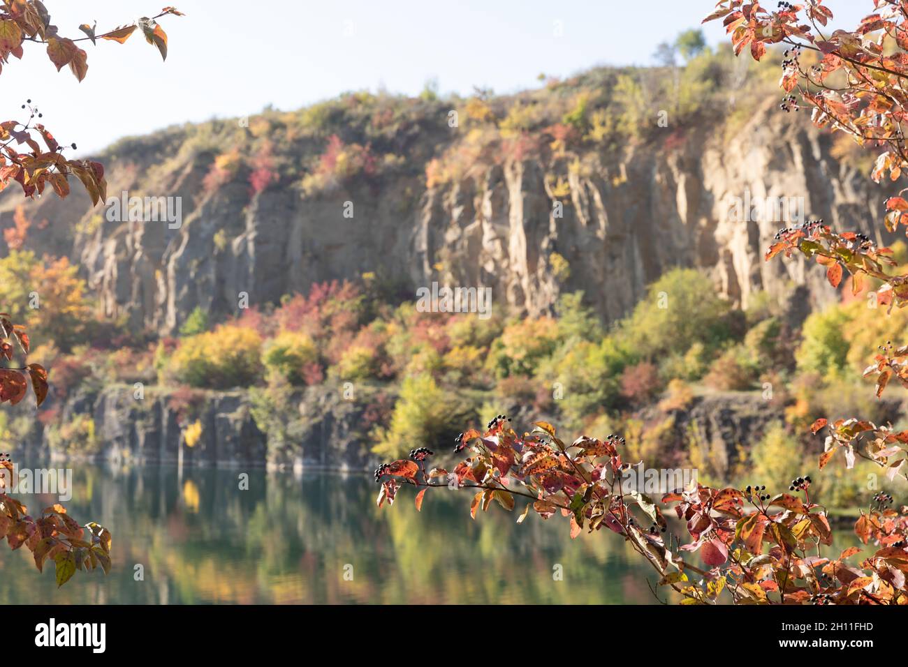 Golden autumn with colourful trees in old flooded quarry. Rocks, lake ...