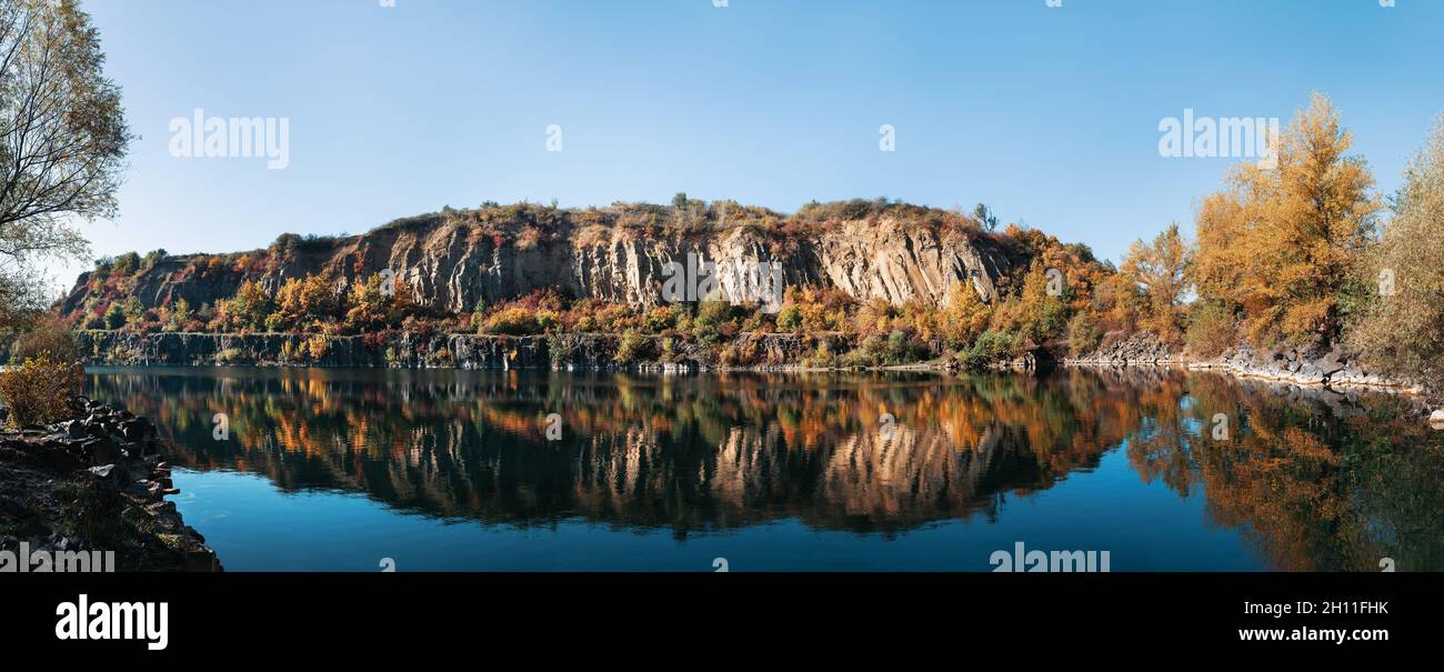 Golden autumn with colourful trees in old flooded quarry. Rocks, lake ...