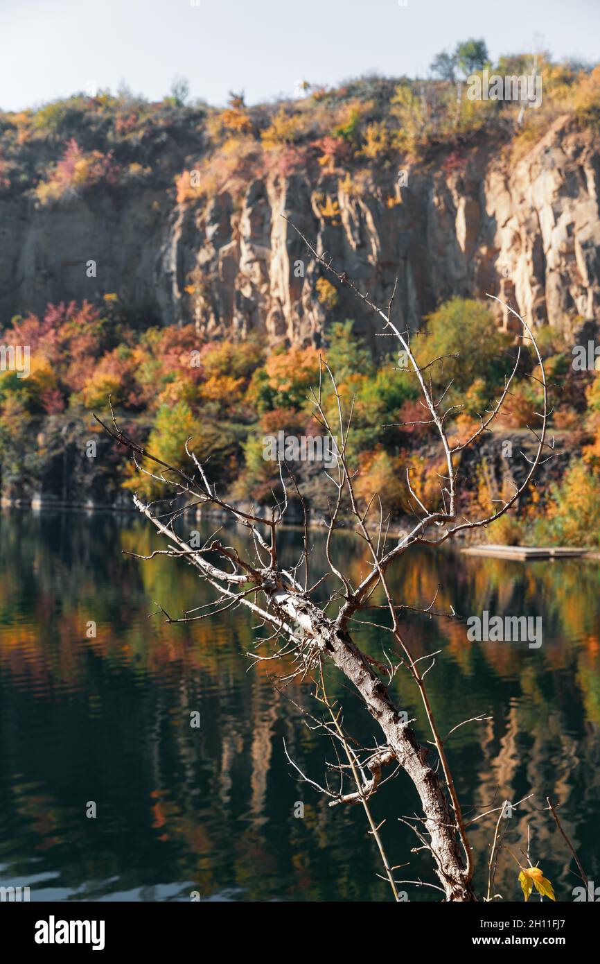 Golden autumn with colourful trees in old flooded quarry. Rocks, lake ...