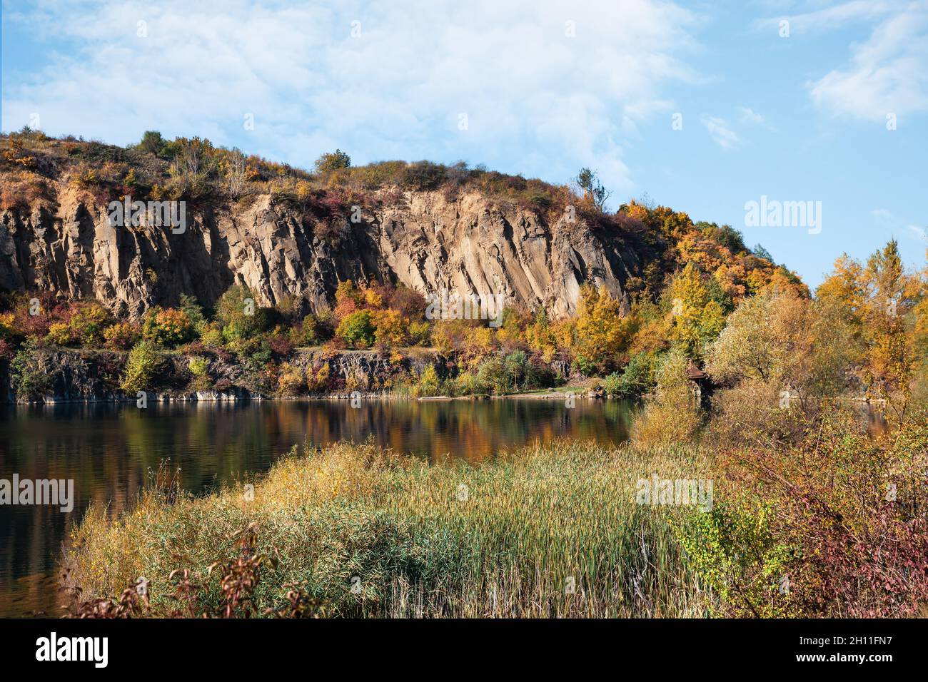 Golden autumn with colourful trees in old flooded quarry. Rocks, lake ...