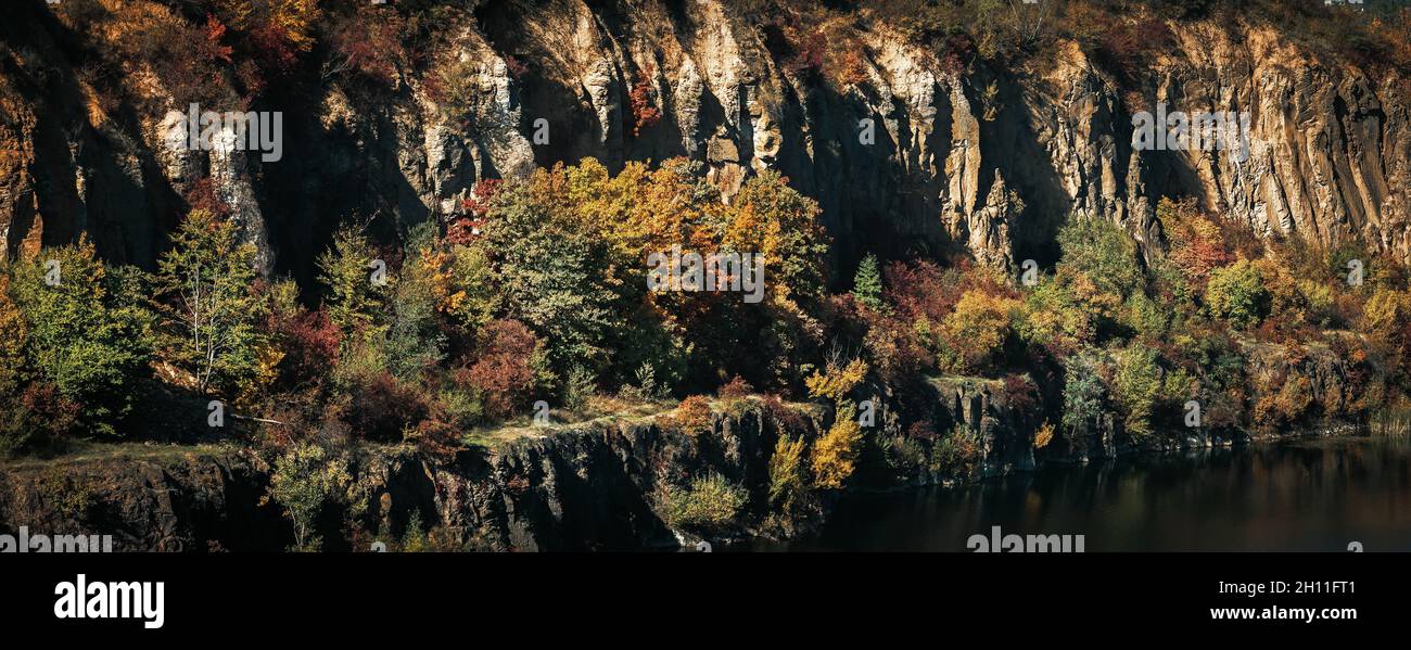 Golden autumn with colourful trees in old flooded quarry. Rocks, lake ...