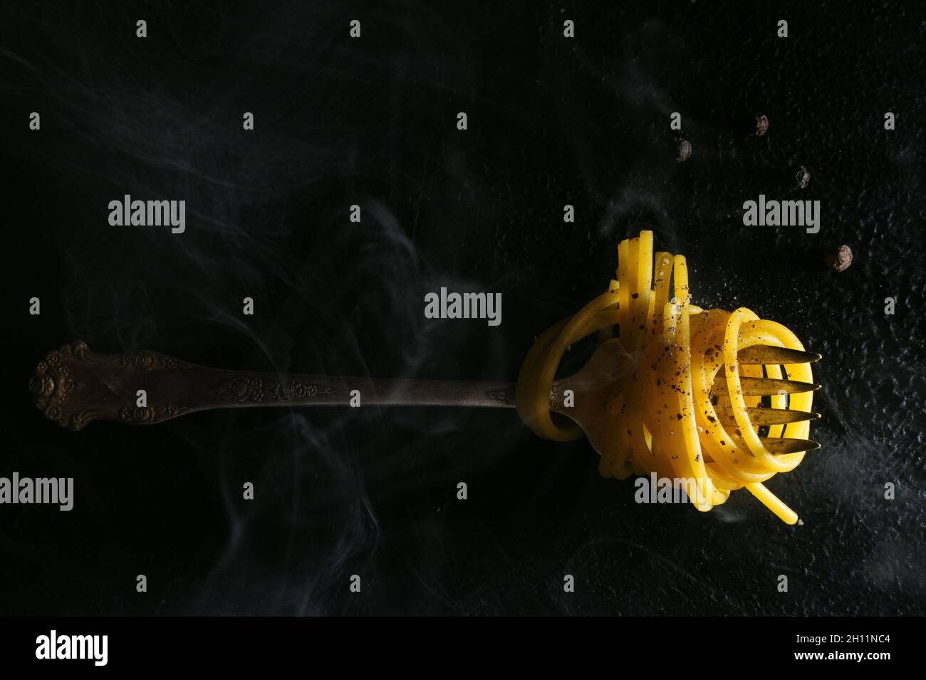 Delicious and hot spaghetti pasta wrapped around a fork on a black ...