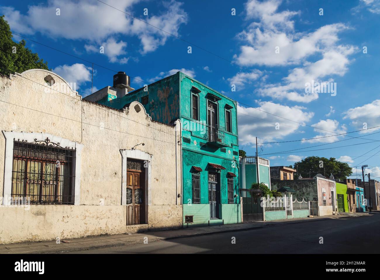 Street with typical Mexican sunlit colorful renovated colonial house ...
