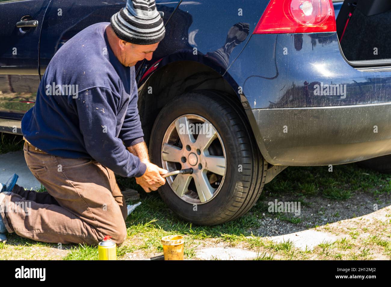 Car mechanic screwing or unscrewing car wheel by wrench at car garage ...