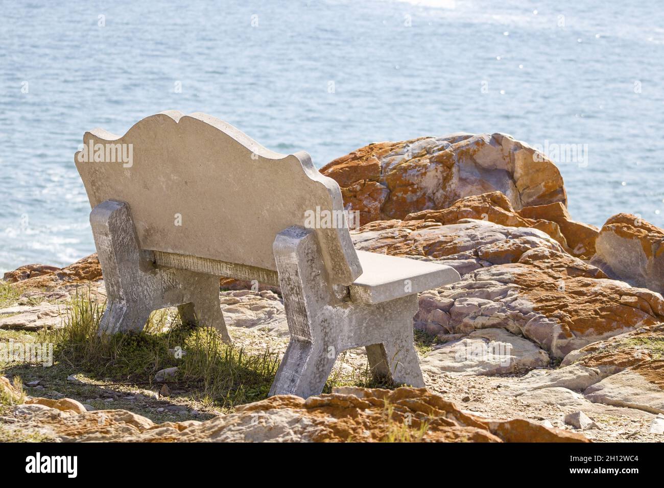 Beautiful shot of a bench on a rocky shore near the sea in South Africa ...