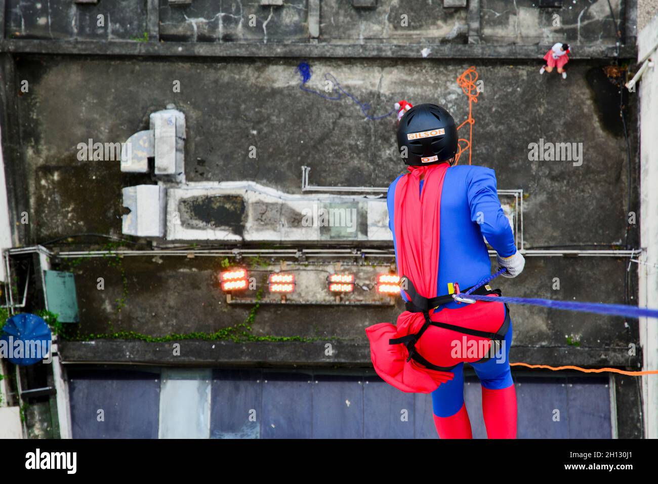 Man dressed as a superhero rappelling down from a tall building ...