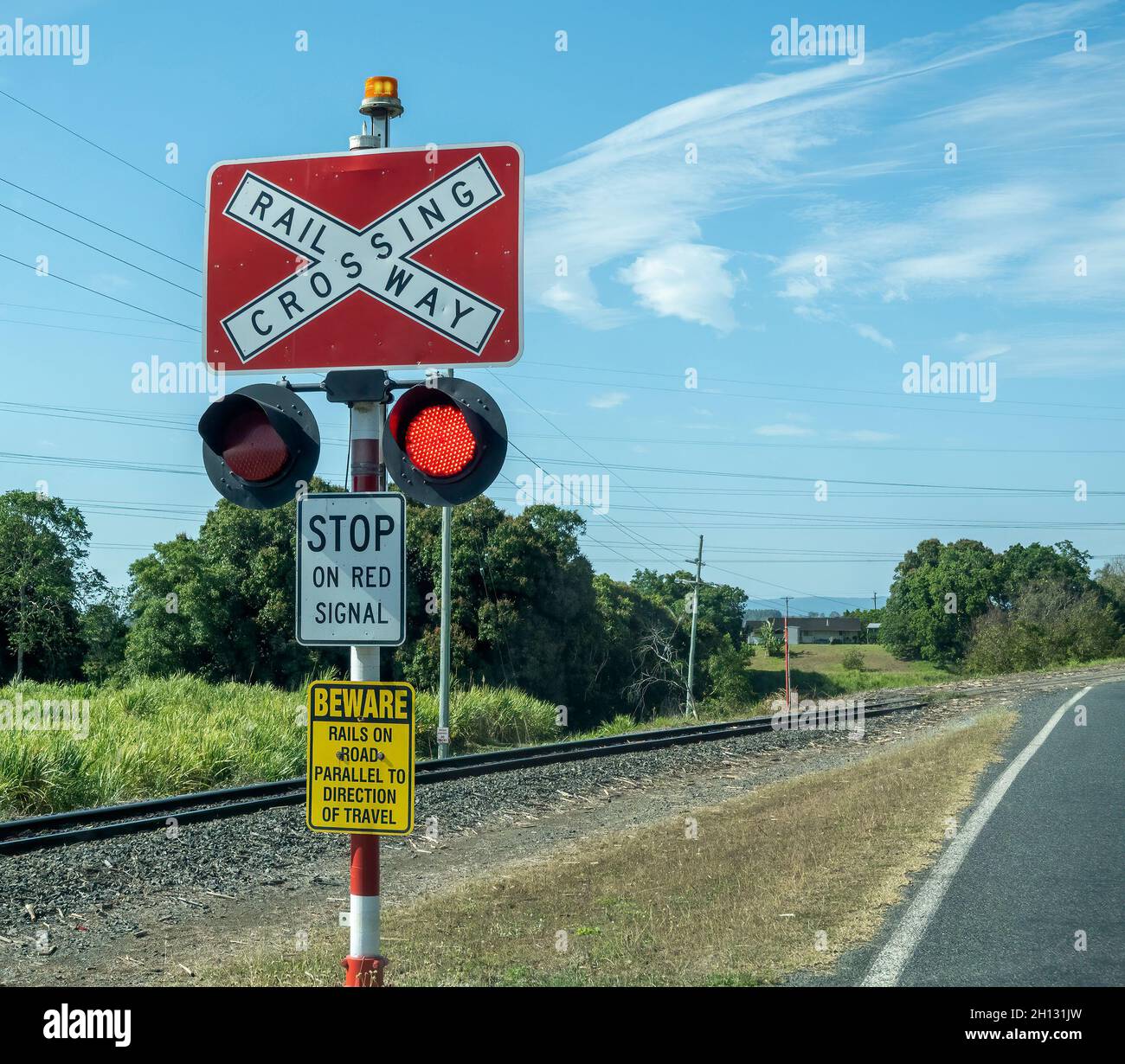 Railway crossing stop go signs with red signal on, rural train tracks ...