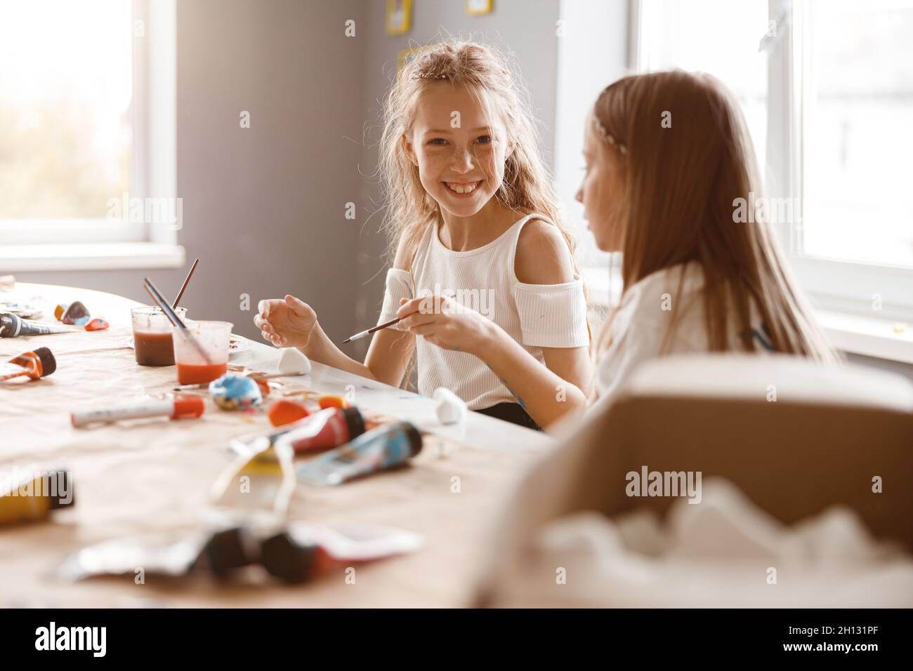 Two girlfriends talking while painting with watercolors at school Stock ...