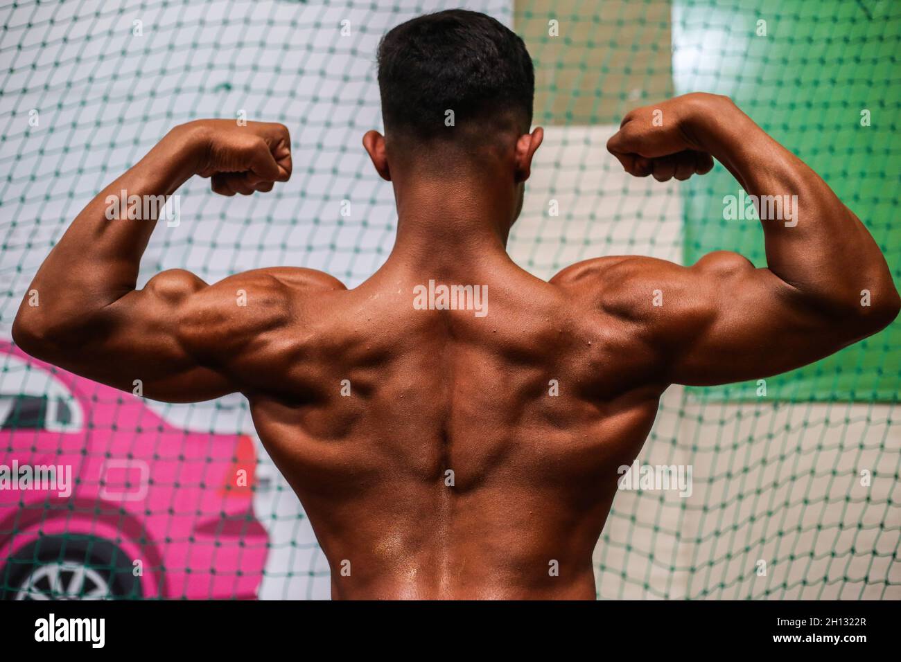 An athlete displays his body muscles during the championship.The ...