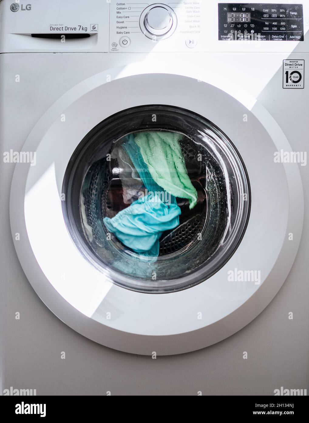Blue and green clothes spinning in side-load washing machine Stock ...