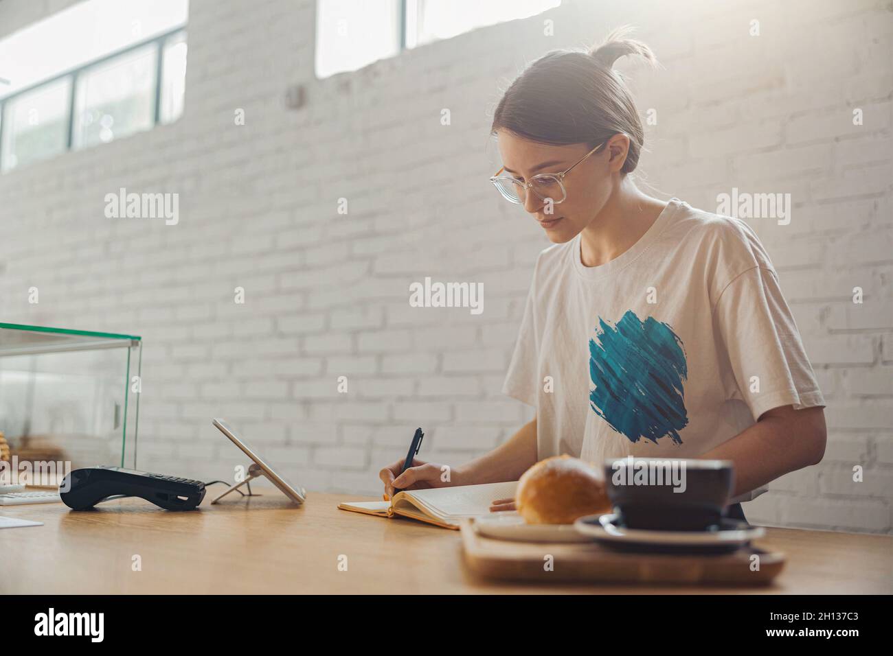 Charming female barista writing in notebook in coffee shop Stock Photo ...