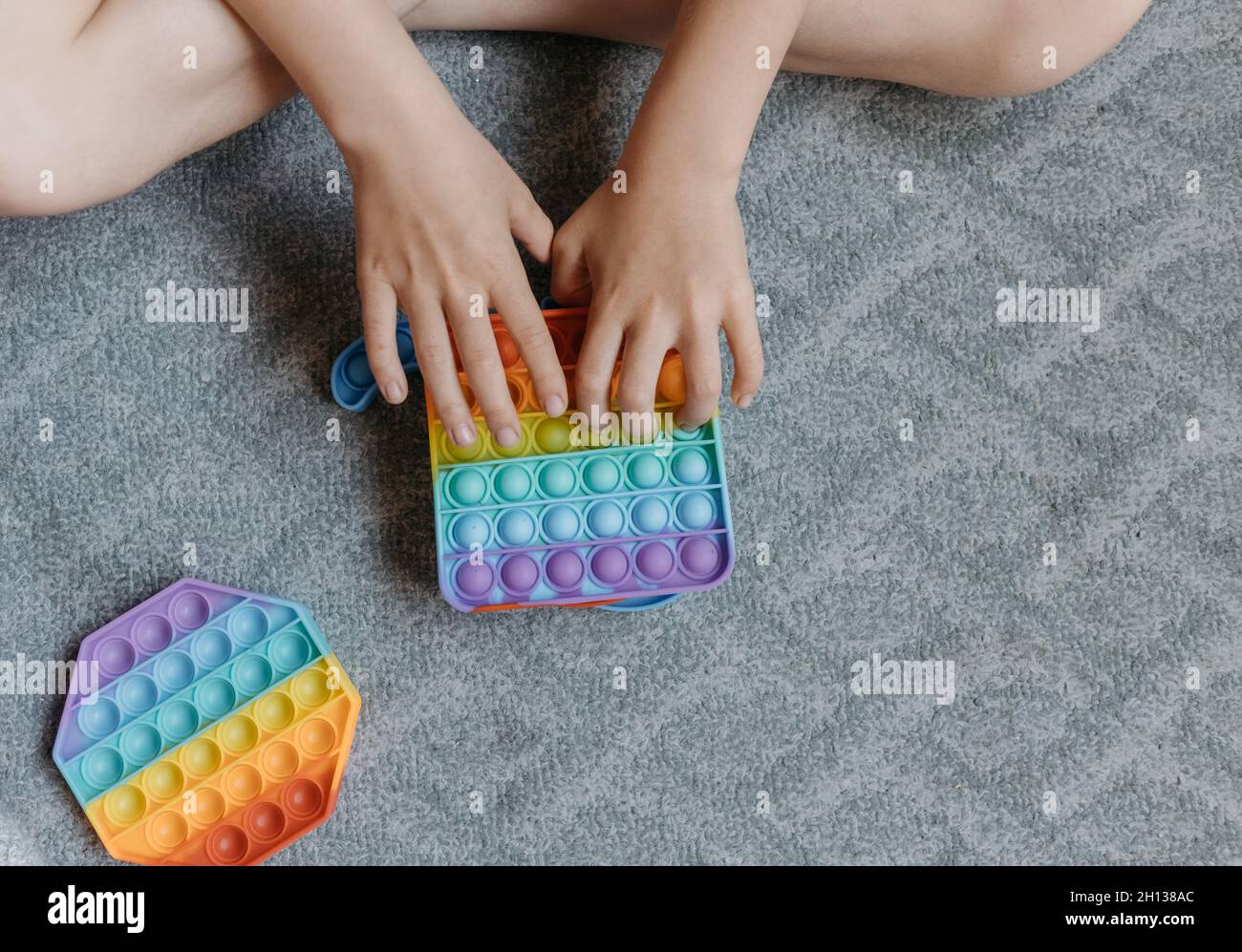 View from above to children playing with pop it toys. Happy childhood ...