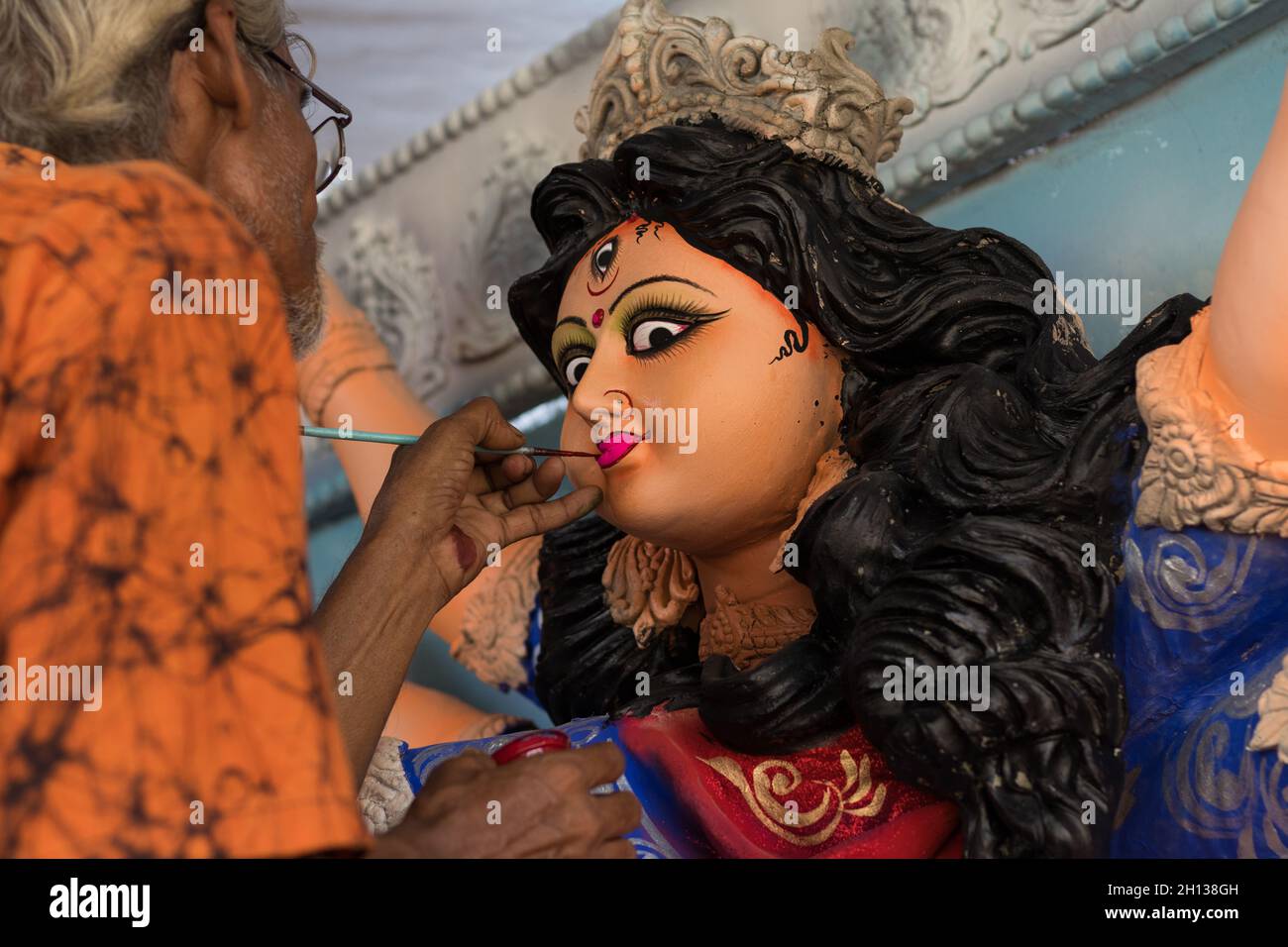 An old artist painting lips of Durga idol Stock Photo - Alamy