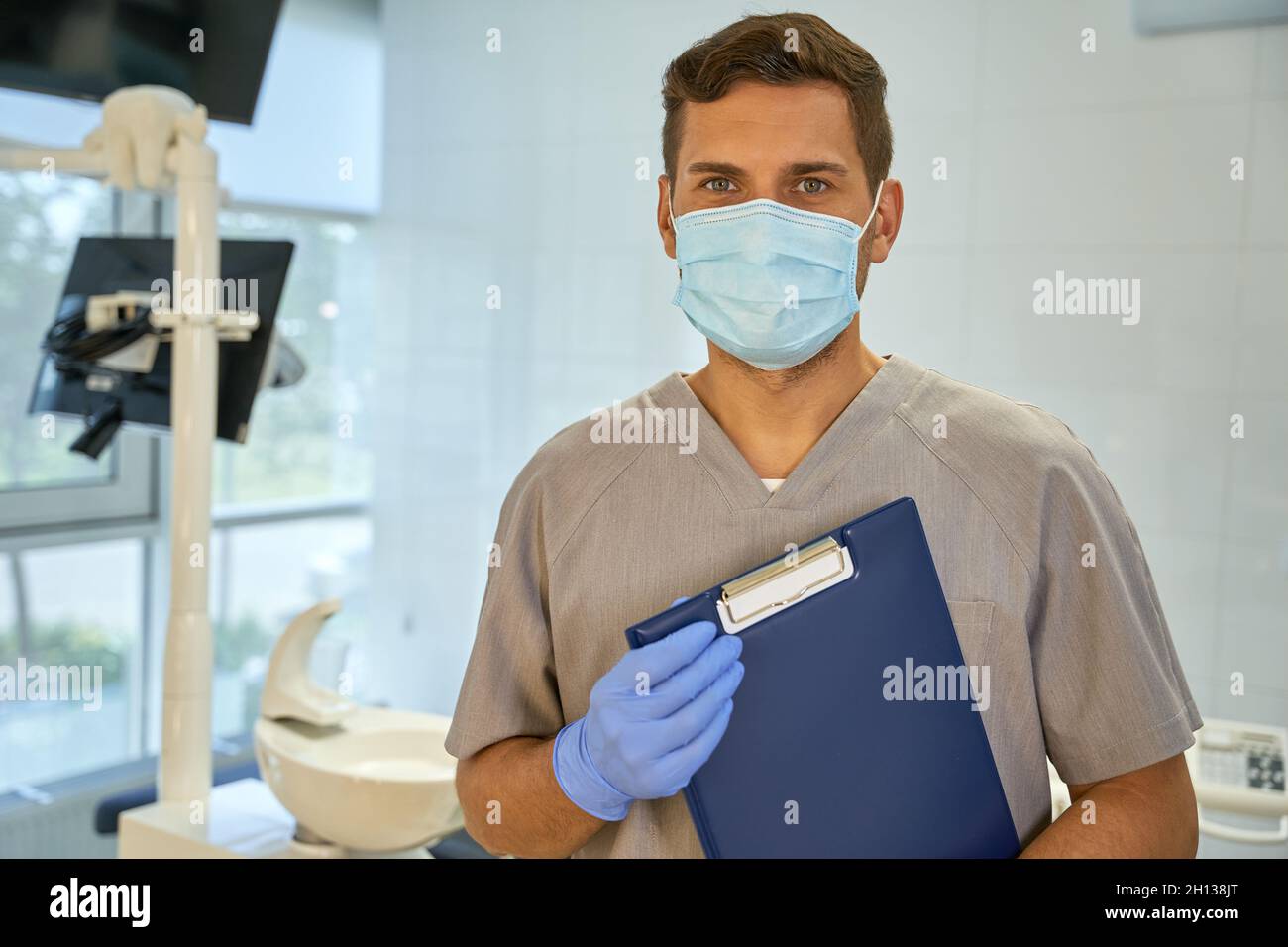 Attractive young dentist posing near dental chair Stock Photo - Alamy