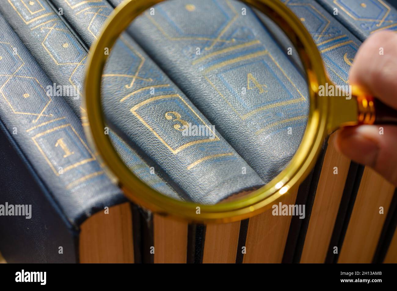 A man looks at a lot of books through a magnifying glass. A hand with a ...