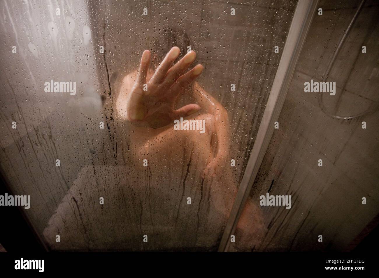 A woman crumbles in the shower, image illustrating domestic violence ...