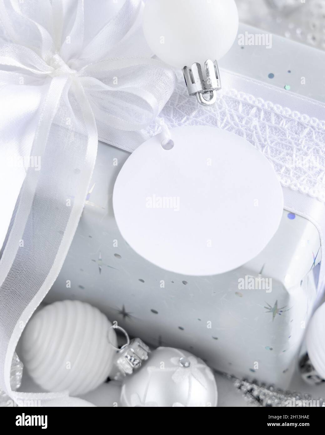 Wrapped present with a white bow and round paper gift tag on a white ...