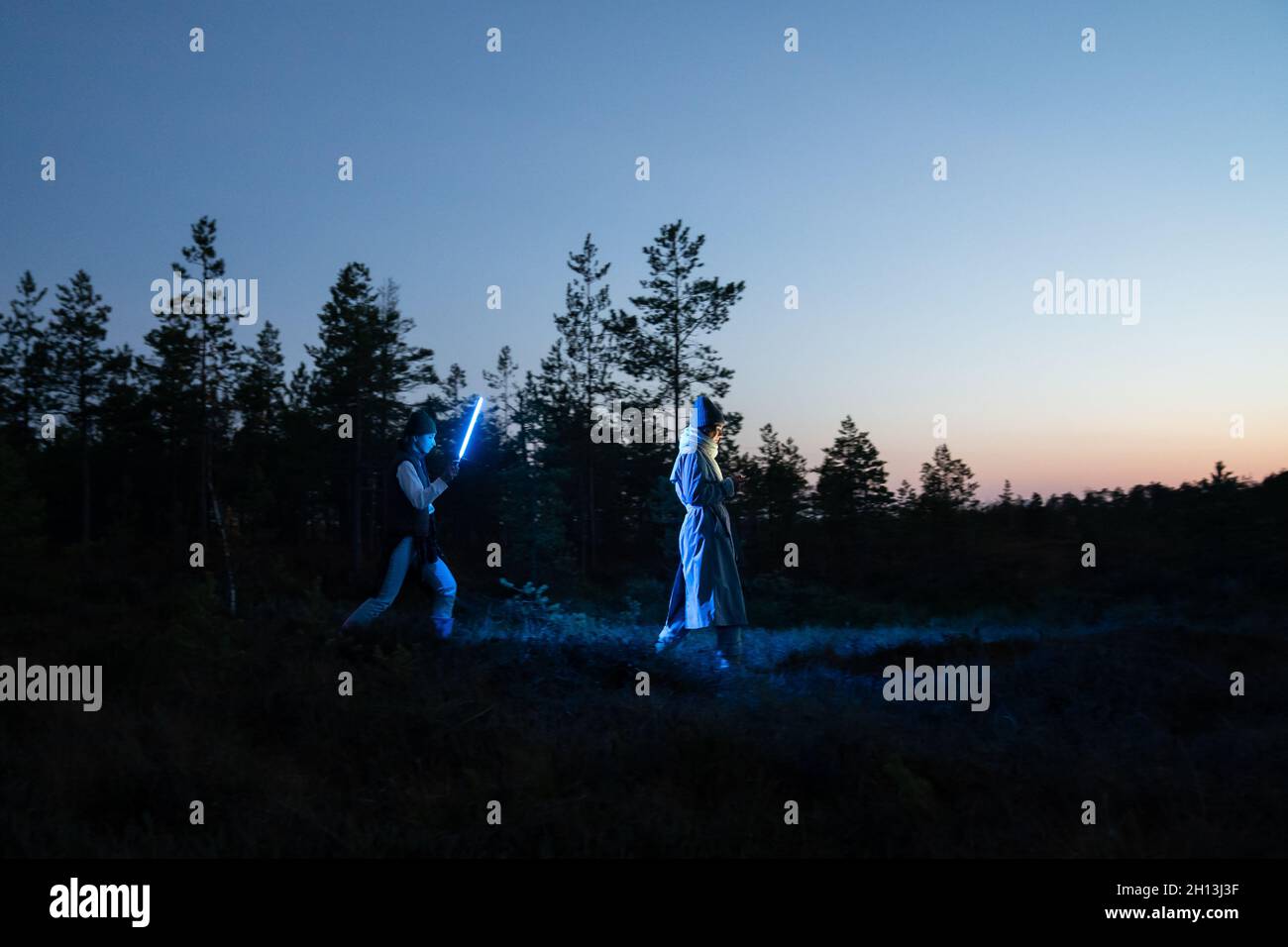 Two women walk at night on swamp using led lamp to follow trail for ...
