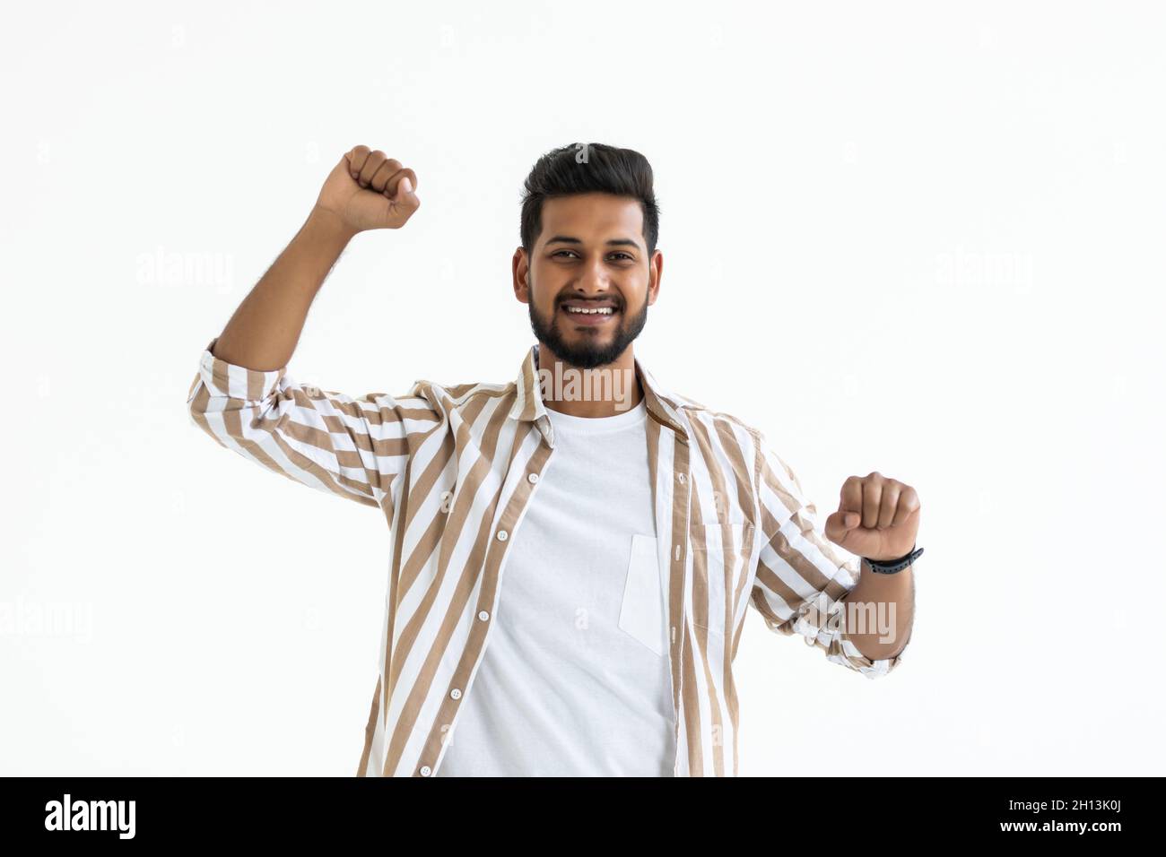 Happy young Indian man gesturing and smiling while standing against ...