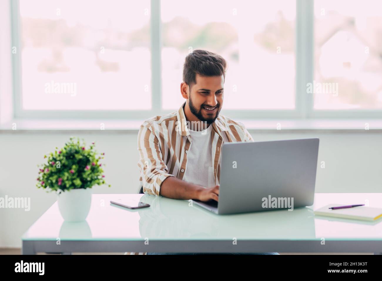 young indian man working at office and talking on mobile Stock Photo ...