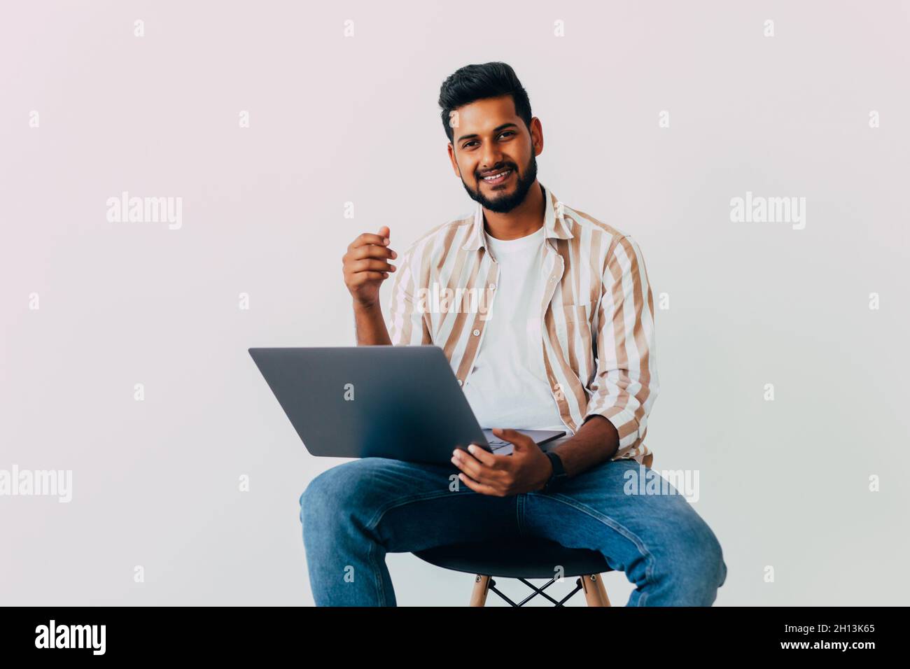 Portrait of business Indian man using laptop computer, looking side and ...