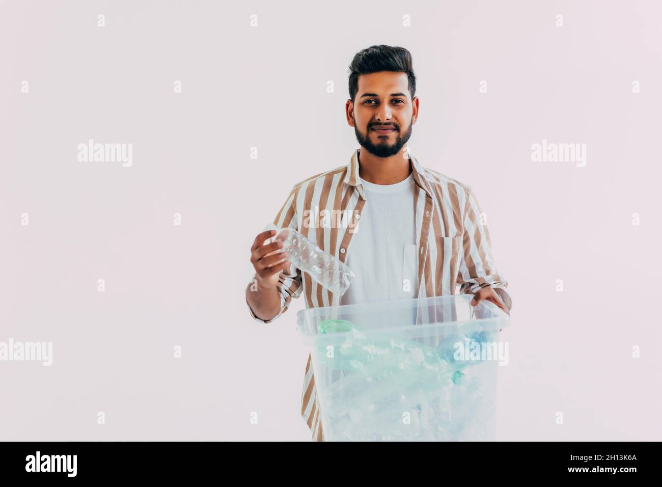 Portrait of young man holding recycling bin isolated on white Stock ...