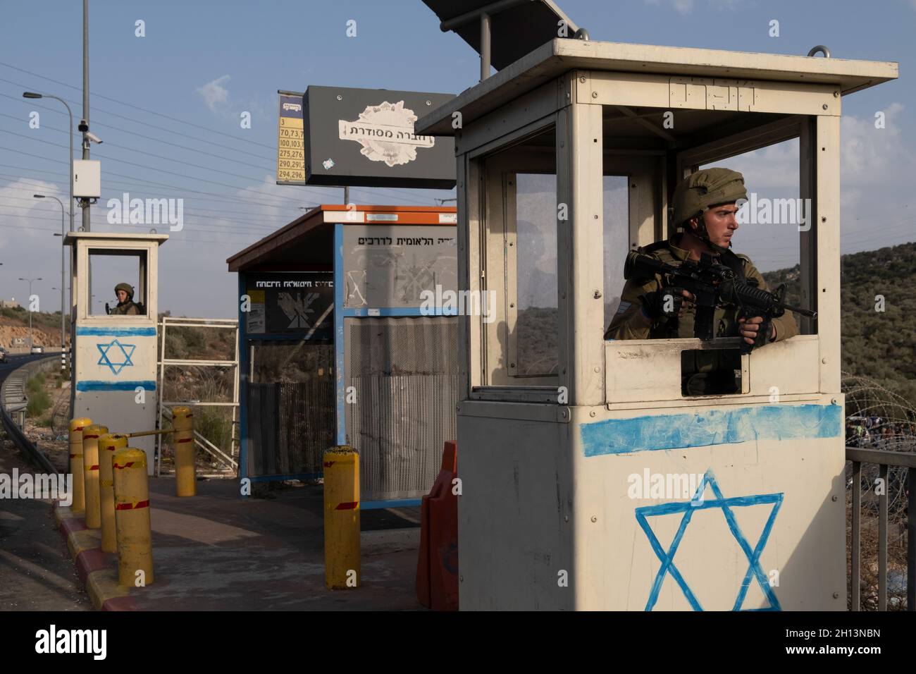 Israeli soldiers stand guard behind concrete blocks at a bus station ...