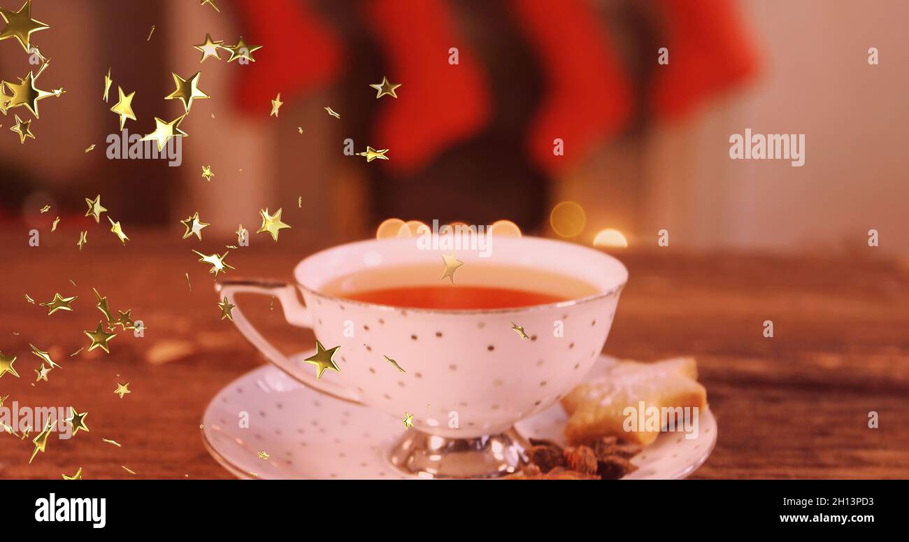 Image of glowing stars falling over cup of tea with christmas cookies ...