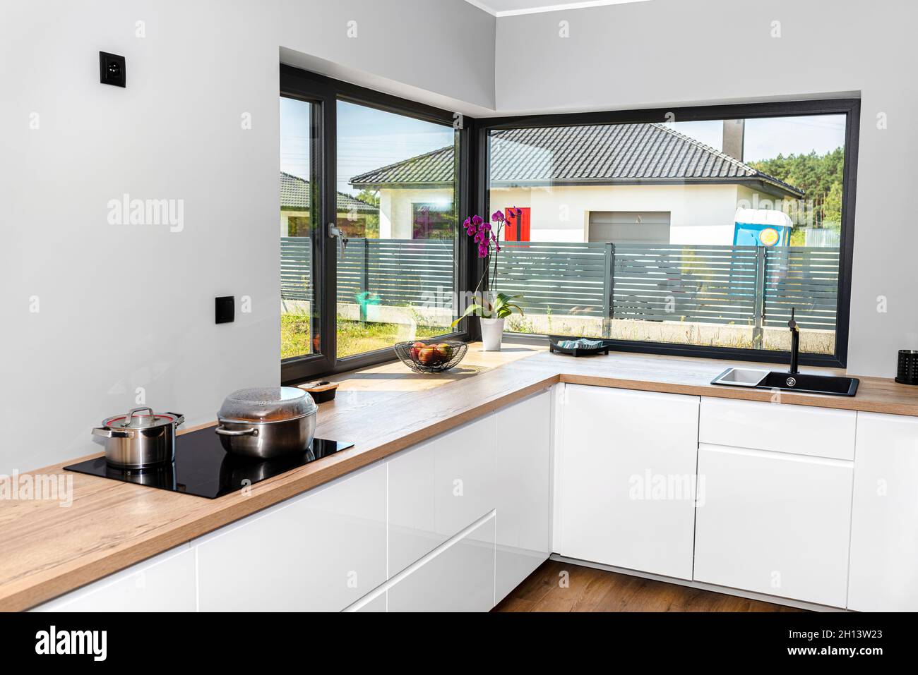 Large corner window in a modern kitchen with built-in cabinets against ...