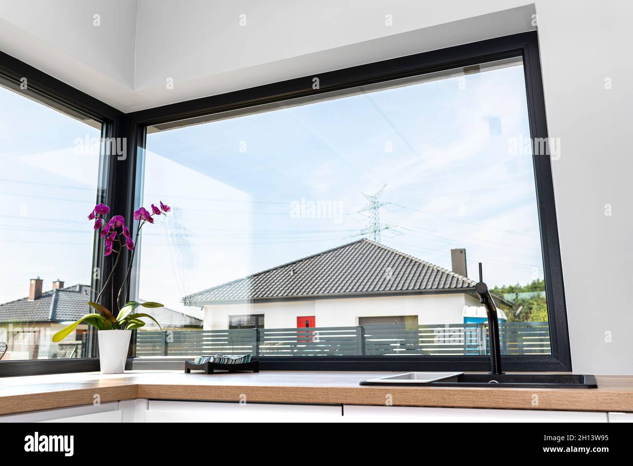 Large corner window in a modern kitchen with built-in cabinets against ...