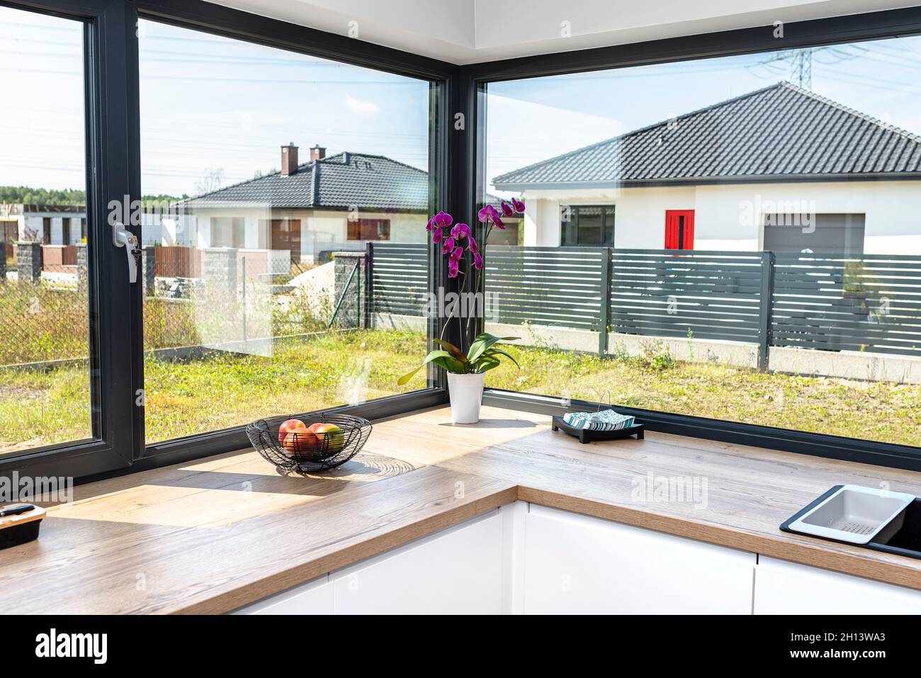 Large corner window in a modern kitchen with built-in cabinets against ...