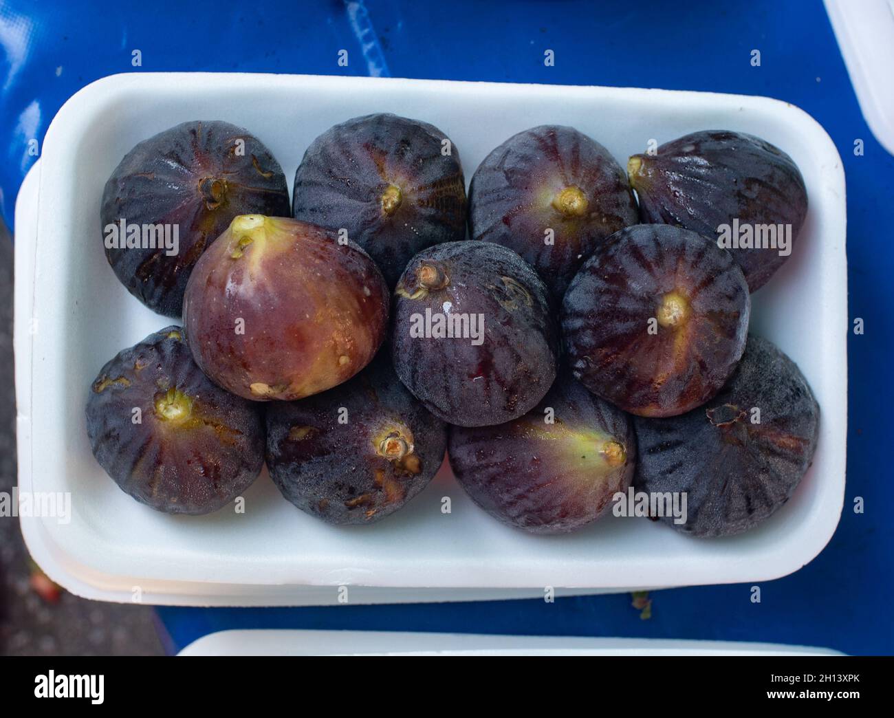 Fresh purple figs packaged on plastic substrates on the counter on ...