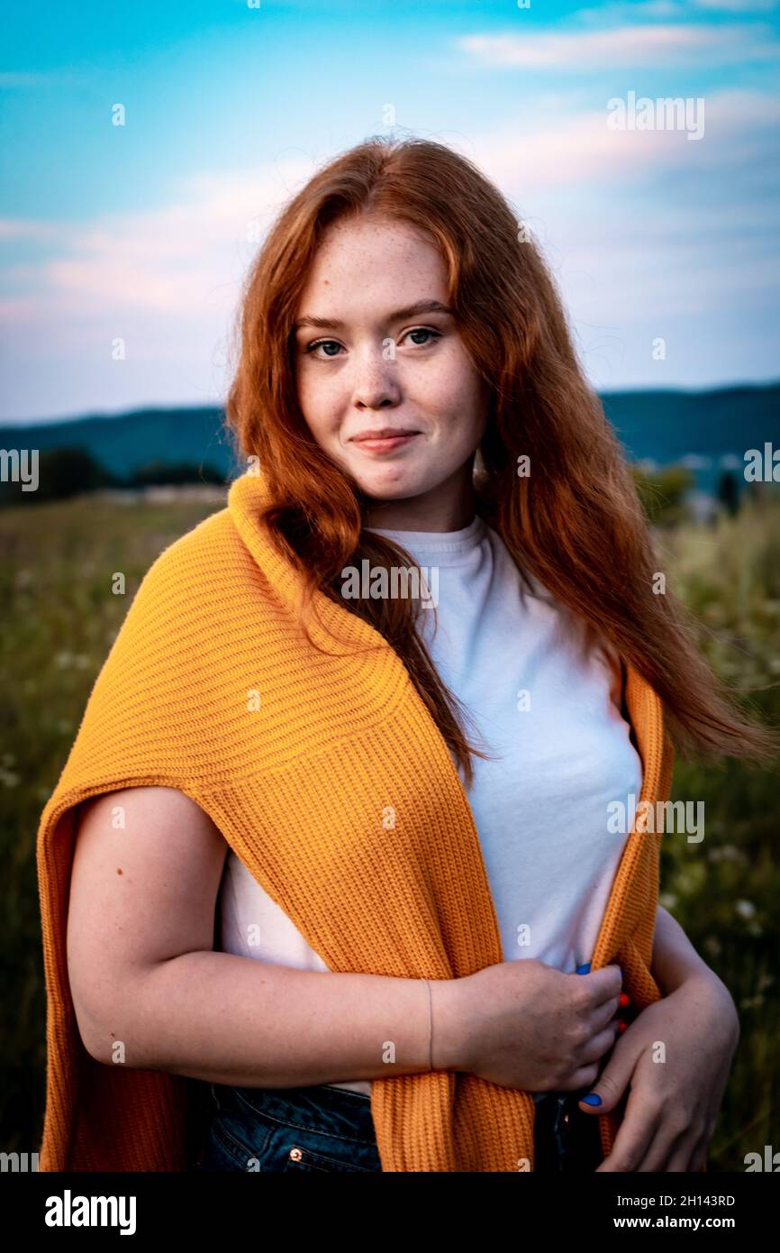 Close-up street portrait of a young happy smiling red-haired girl with ...