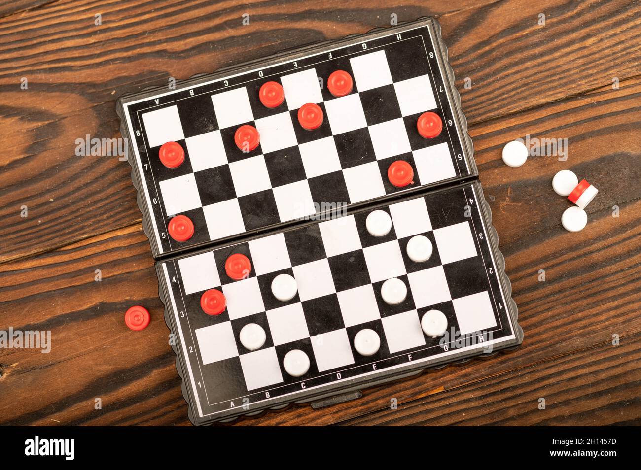 A board for playing checkers with chips on a wooden table, close-up ...