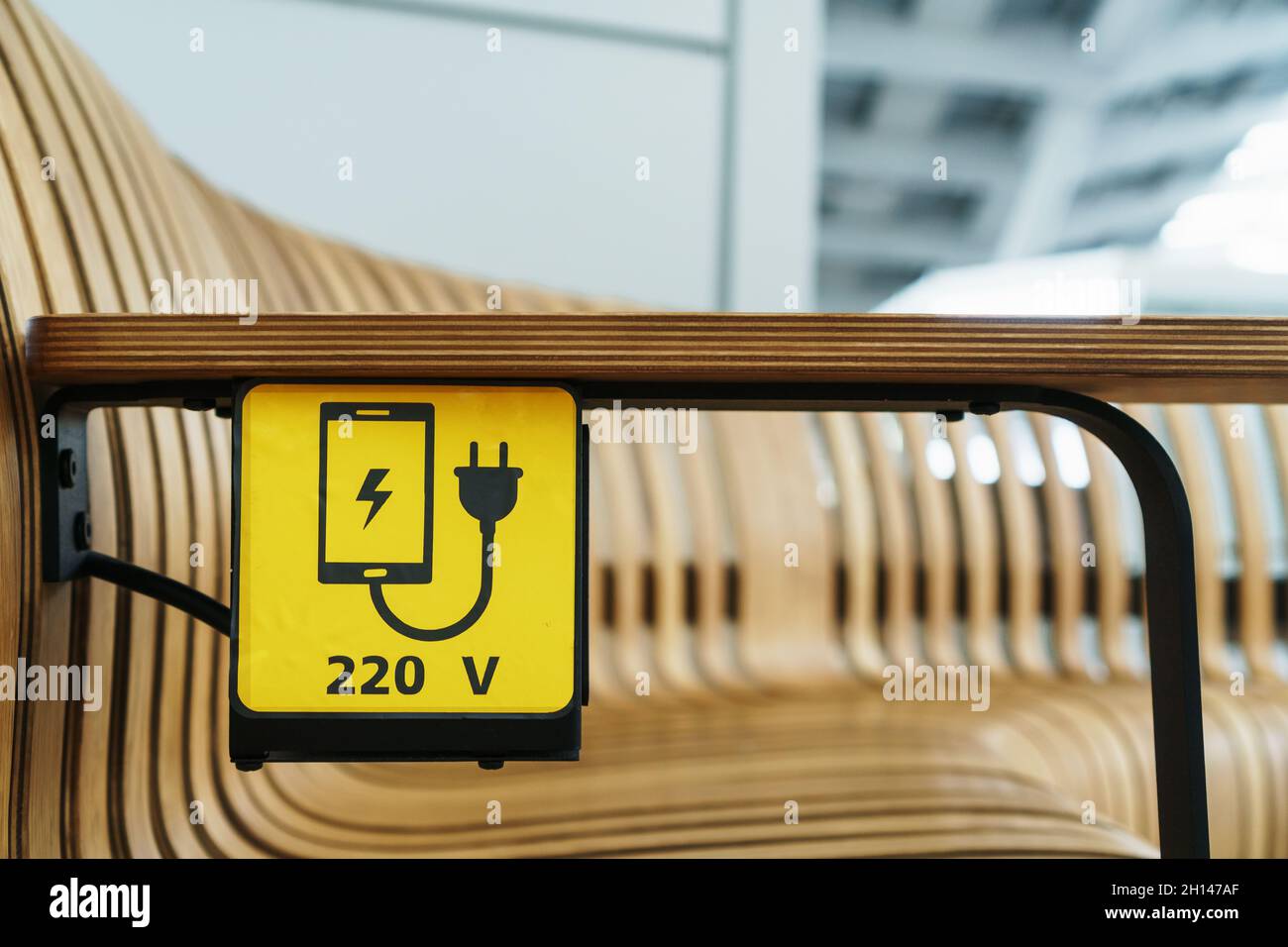 A socket with a device charging sign on a wooden bench at the airport ...
