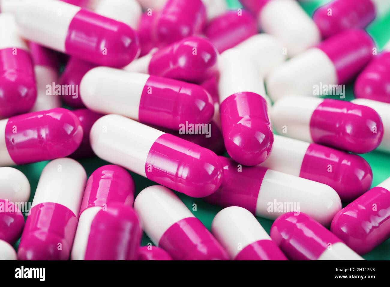 Pink medical pills on a black background. Top view as a full-screen ...