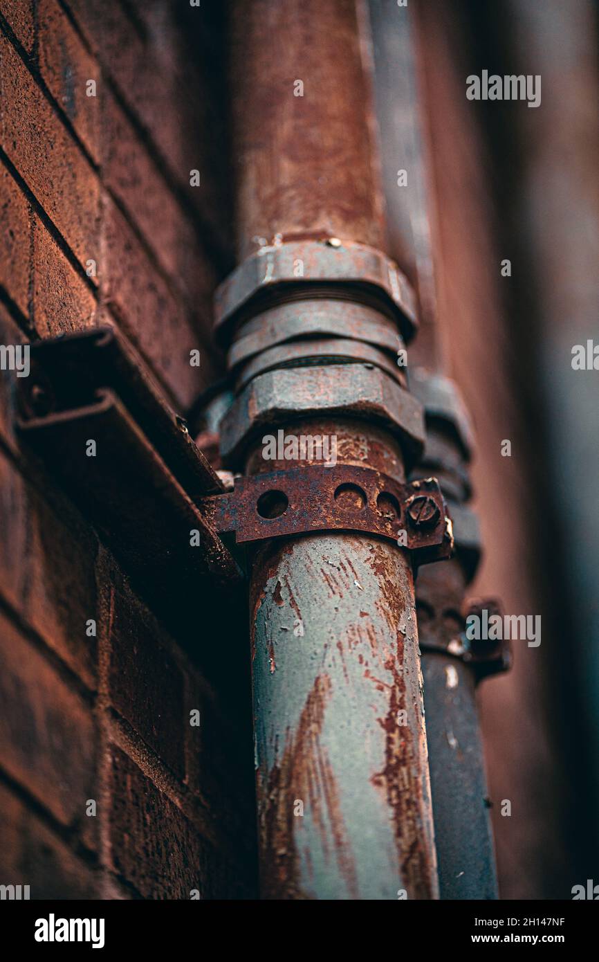 Vertical shot of old and rustic metal pipes on brick-walled building ...