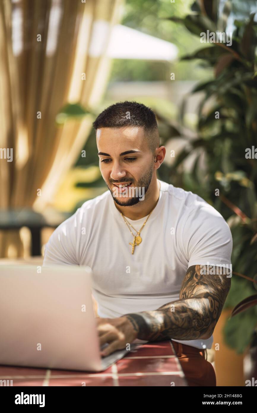 Vertical shot of a young Caucasian male working with a laptop from an ...