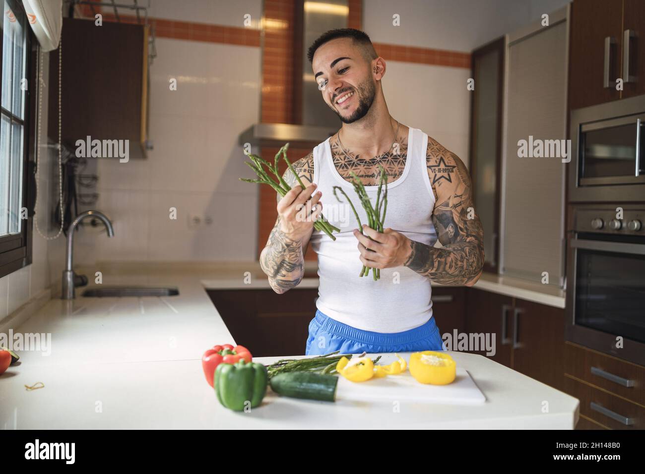 Tattooed Caucasian male athlete preparing healthy food in the kitchen ...