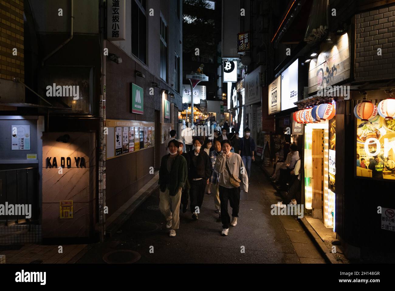 People wearing masks walk through an alley in Shibuya district, Tokyo ...