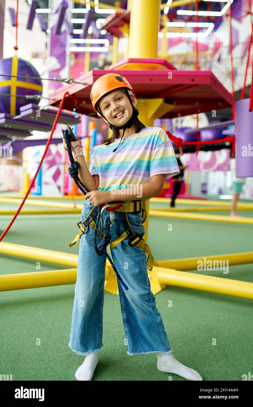 Cheerful little girl in helmet poses on zip line Stock Photo - Alamy