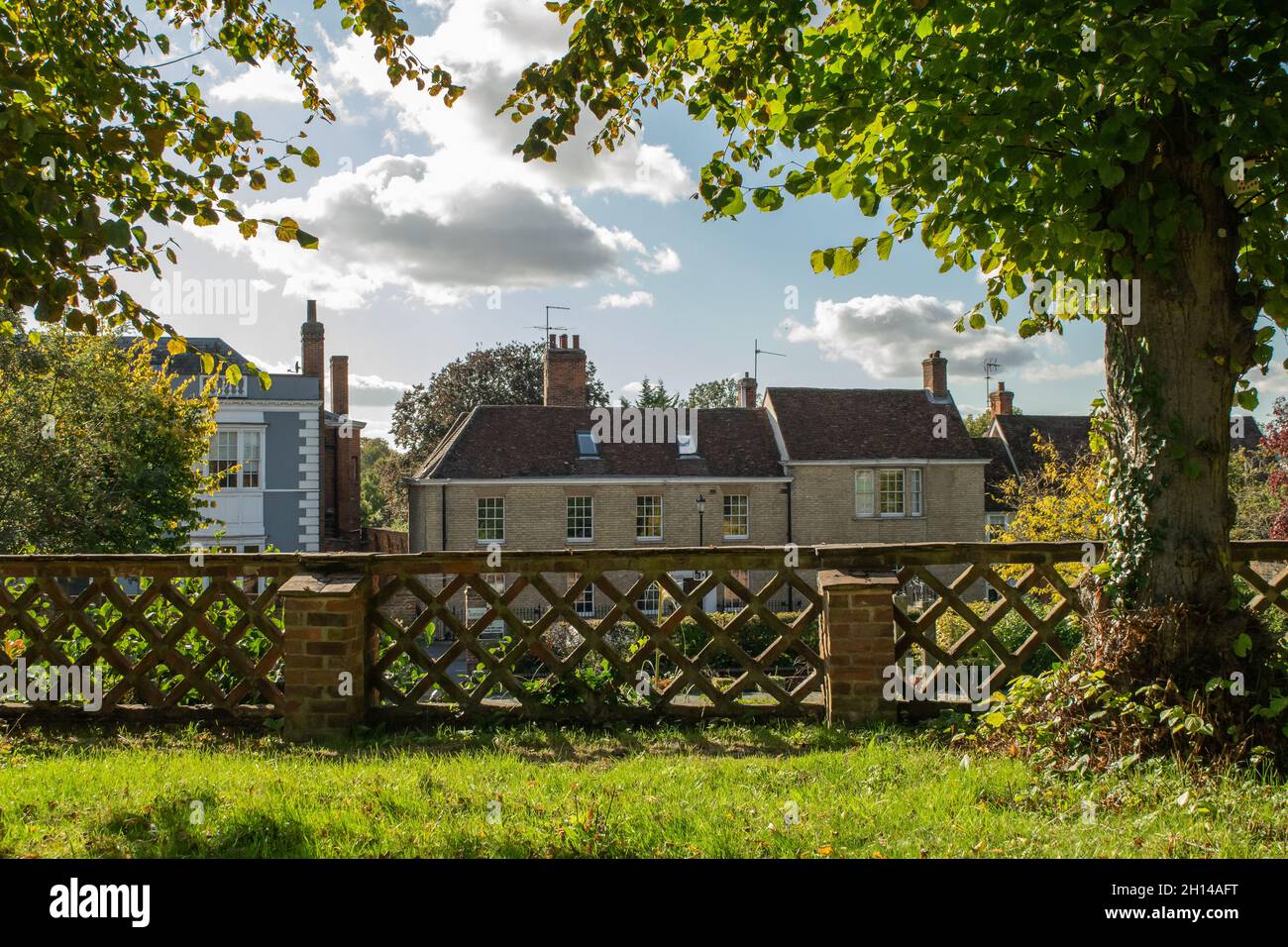 Wooden fence on grass in front of traditional British brick houses at ...