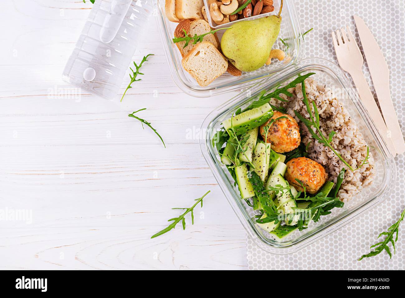 Lunch box filled with oatmeal, cucumber salad, and nuts, bread, pear on ...