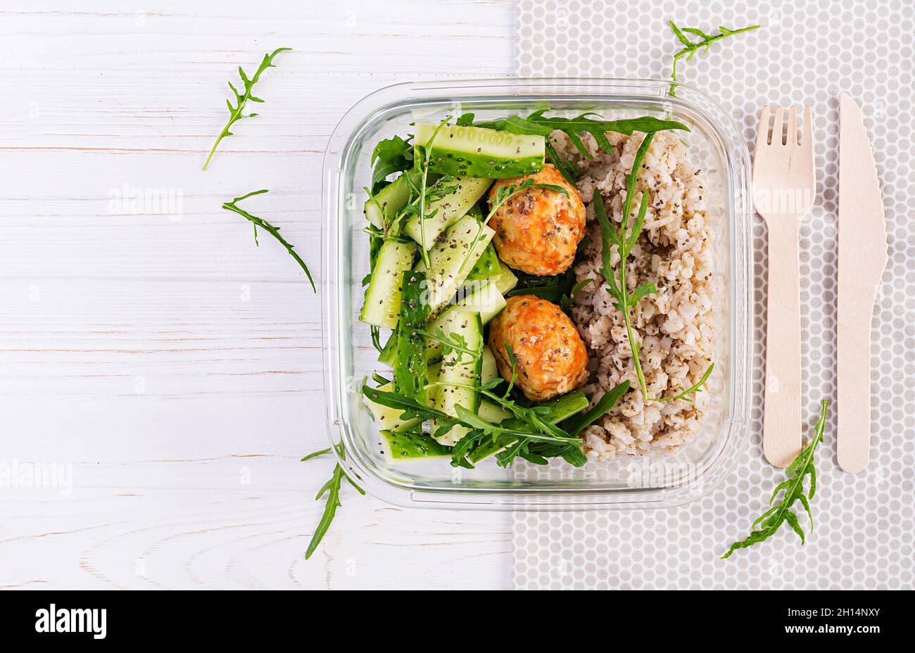 Lunch box filled with oatmeal, cucumber salad, and nuts, bread, pear on ...