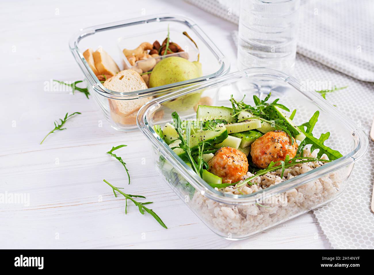 Lunch box filled with oatmeal, cucumber salad, and nuts, bread, pear on ...
