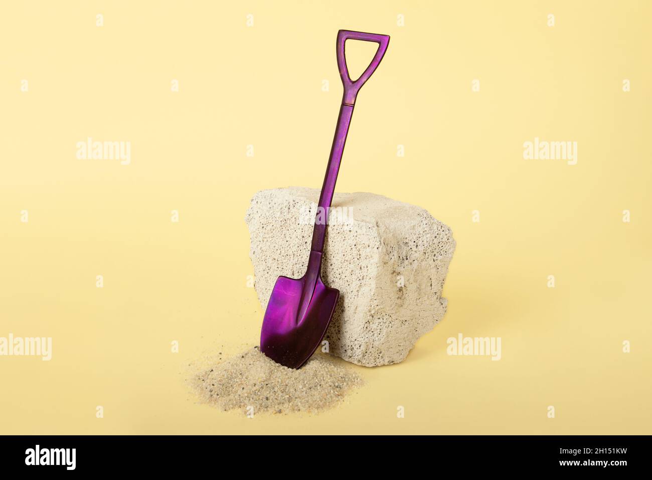 Decorative shovel staying near stone.Quartz sand on the yellow ...