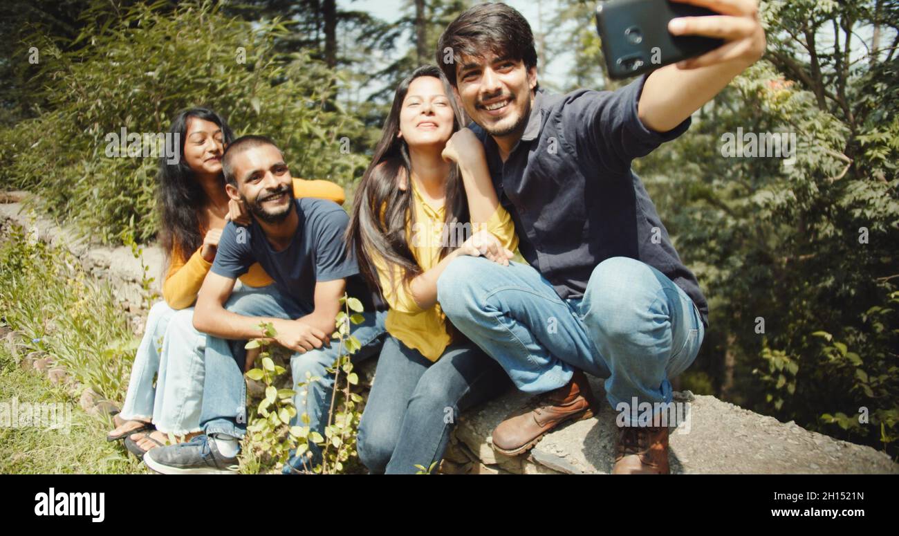 Shot of four young male and female South Asian friends taking a selfie ...