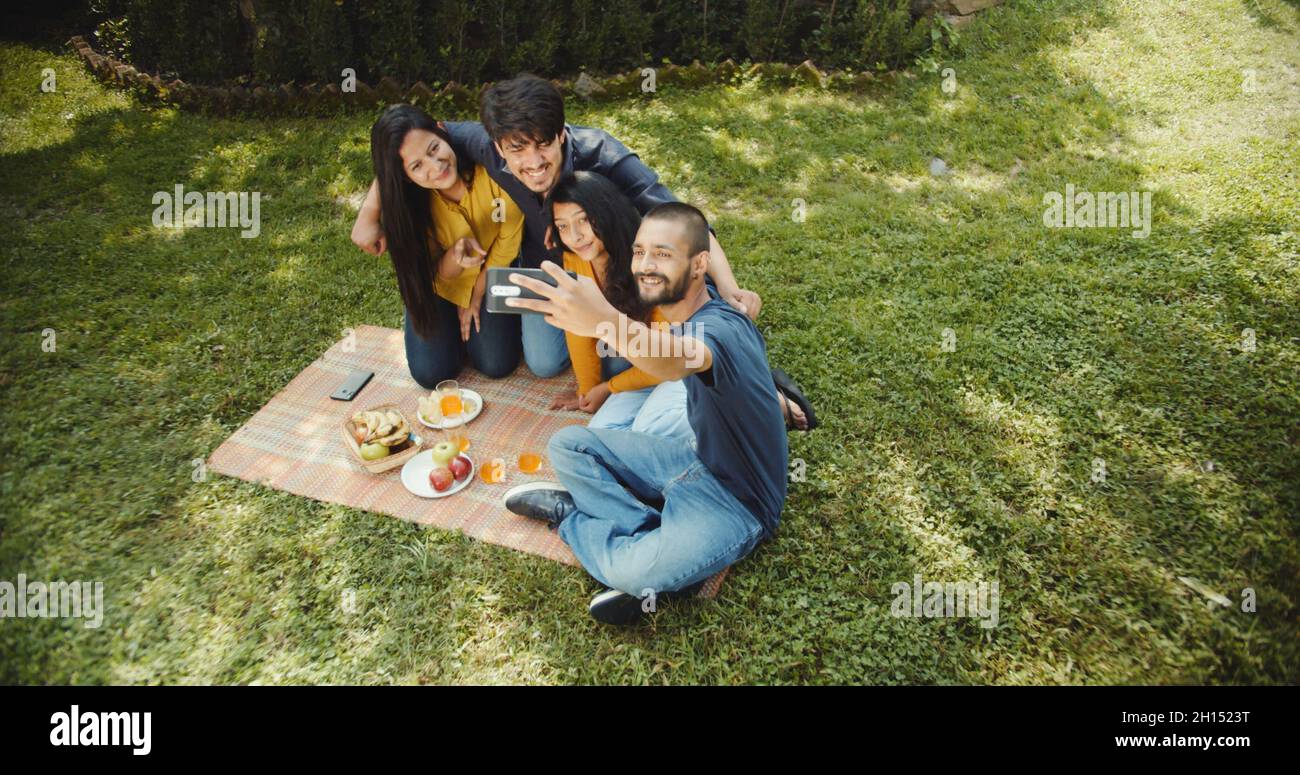 Shot of four young South Asian friends taking a selfie at a picnic ...