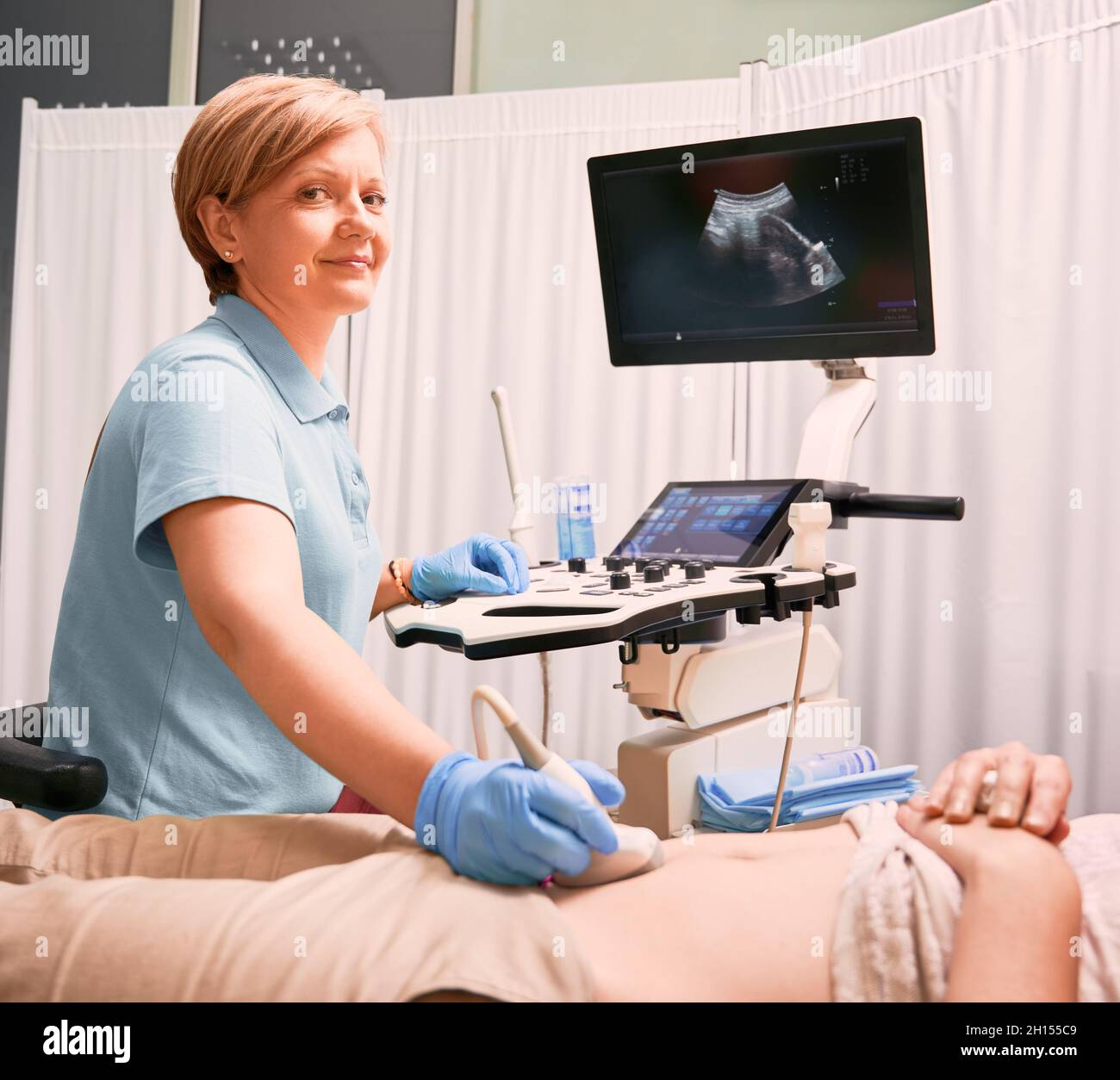 Female physician in sterile glove examining woman with ultrasound ...